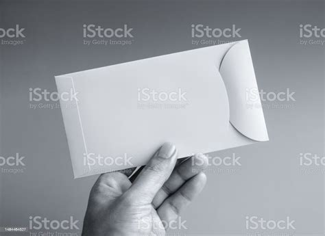 흰 봉투를 들고 있는 손 세로 스타일 회색 배경 흑백 스타일 손에 빈 편지 패킷을 닫습니다 비즈니스와 금융 개념 봉투에 대한