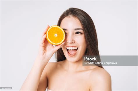 하얀 배경에 손에 오렌지를 손에 들고 어두운 긴 머리카락을 가진 행복한 미소 아시아 여성의 아름다움 재미있는 초상화 고립 20 24세에 대한 스톡 사진 및 기타 이미지