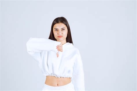 Изображение модели серьезной молодой девушки показывает палец вниз Бесплатно Фото