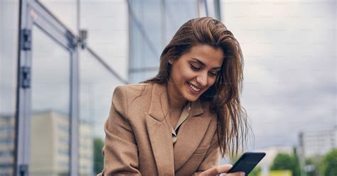 미소는 레일에 기대어 가제트를 가진 세련된 잘 생긴 젊은 백인 여성 기업가를 기쁘게 생각합니다 사진 Unsplash의 사무실 이미지