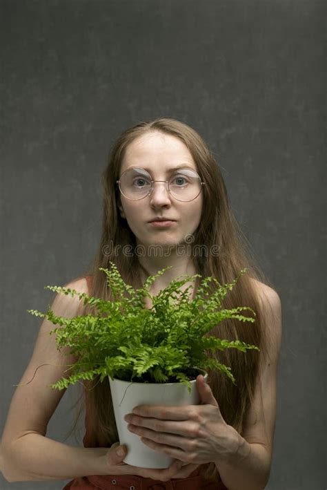 Girl With Long Hair Wearing Round Glasses Holds Green Houseplant