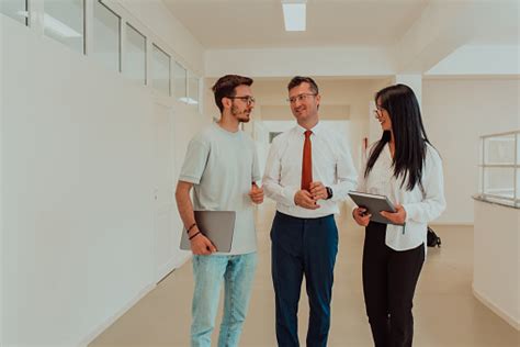 감독은 대기업의 현대적이고 넓은 복도에서 비서 및 젊은 프로그래머와 대화를 나누며 다양한 비즈니스 주제와 프로젝트에 대해 논의합니다 감독에 대한 스톡 사진 및 기타 이미지