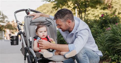 유모차에 아기 딸과 함께 걷는 백인 자랑스러운 아버지 가족 아빠와 딸은 여름날 도시 거리에서 야외에서 함께 있습니다 아이들과