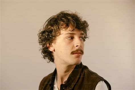 곱슬머리를 한 남자가 옆을 쳐다보고 있다 사진 Unsplash의 초상 이미지