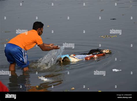 A Man Floating Hindu Goddess Saraswati Idol For Immersion On The Ganges