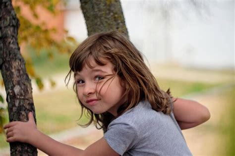 Premium Photo Close Up Of Smiling Girl On Tree Trunk