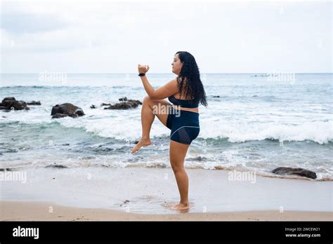 Fitness Woman Standing Doing Leg Exercises On The Beach Sand Against