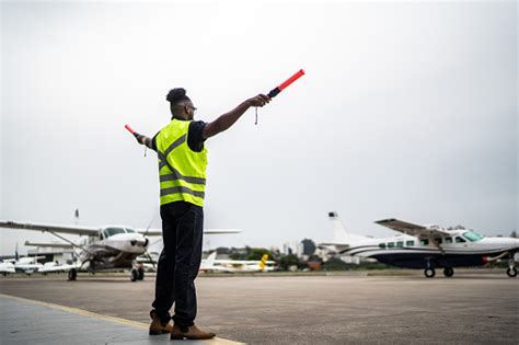 Pria Memberi Isyarat Kepada Pilot Dengan Tongkat Marshalling Di Bandara