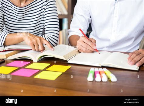 Young Students Classmates Help Friend Catching Up Workbook And Learning Tutoring In A Library