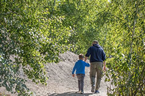 아버지는 아버지와 아들이 함께 보내는 시간을 즐기는 아들의 손을 잡고 행복한 아이는 이빨을 드러내며 웃고 있다 가을 숲 부모 자식 야외에서 행복한 가족 2명에 대한 스톡
