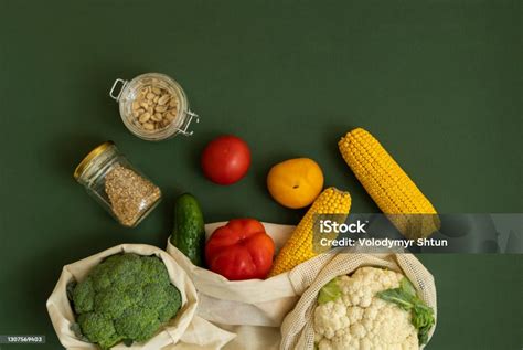 녹색 표면에 유리 항아리에 에코 가방과 견과류야채 후추 토마토 옥수수 오이 브로콜리 콜리플라워 를 재사용 가능한 쇼핑 에코 친화적 인 면 직물 가방 제로 폐 플라스틱 무료