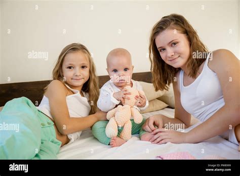 Three Girls Sisters In The Morning In A White Bedroom On The Bed After