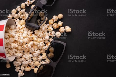 빨간색과 흰색의 캐러멜 팝콘과 안경이 흩어져있는 양동이가 검은 배경 상단보기에서 3d 영화를위한 것입니다 영화관을위한 배너 또는