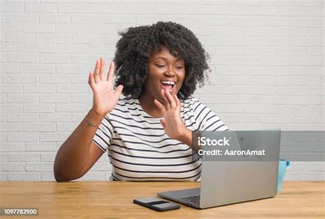 컴퓨터 노트북 매우 행복 하 고 흥분 상자 식 큰 웃음 소리는 승리를 축 하 하 고 손을 사용 하 여 테이블에 앉아 젊은 아프리카계 미국인 여자 공부에 대한 스톡 사진 및
