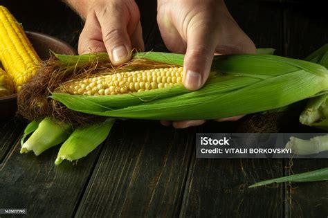 요리사는 요리하기 전에 껍질에서 잘 익은 옥수수를 껍질을 벗깁니다 레스토랑 주방의 작업 환경 일하는 동안 요리사의 손이 클로즈업됩니다 무료 광고 공간 건강한 생활방식에 대한
