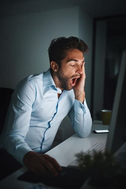 Man Tired And Yawning In Office With Computer For Coding Programming And Software Development At