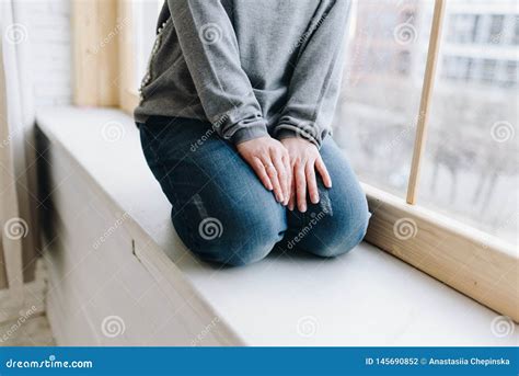 Young Caucasian European Woman Sitting On Windowsill Hands In Her Lap