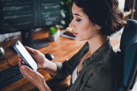 Female Programmer Using Smartphone While Working At Her Desk Coding On