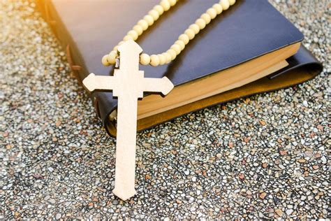 White Ivory Cross Placed On A Dark Brown Notebook Reflects Purity