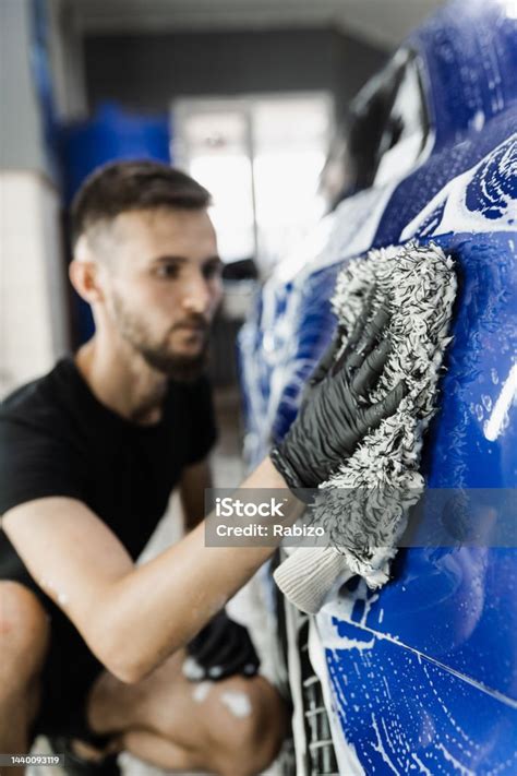 자동차 디테일링 서비스에서 수동 폼 세척을 하는 세차장 차고에서 거품 차체가 있는 극세사 장갑으로 손 씻기 차에 대한 스톡 사진