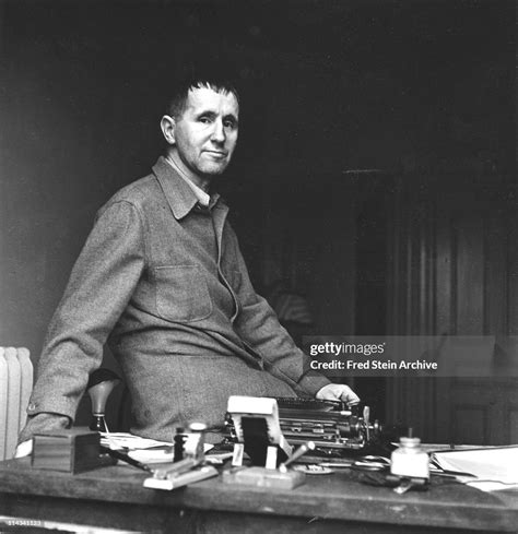 Portrait Of German Playwright Bertolt Brecht As He Sits On A Desk