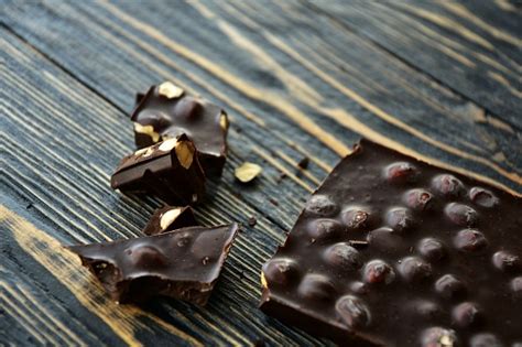 어두운 나무 배경에 헤이즐넛과 초콜릿 조각이있는 다크 초콜릿 바 측면 뷰 긁힌에 대한 스톡 사진 및 기타 이미지 긁힌 음식