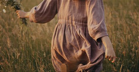 해질녘 여름 초원에서 야생화를 손에 들고 달리는 린넨 드레스를 입은 아름다운 여자 시골에서 자유로운 저녁을 즐기는 소박한