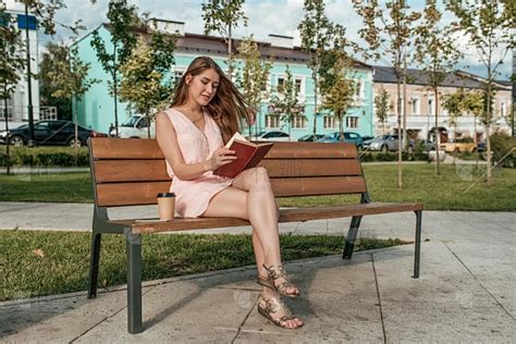 夏天，在城市公园里，女学生坐在长凳上读纸质书。快乐的微笑，读一本艺术小说，一杯茶咖啡，自由的文字空间素材 花瓣网