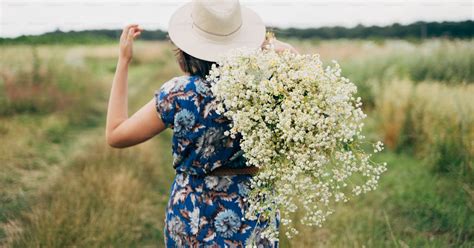 시골의 여름 파란색 빈티지 드레스와 모자를 쓴 세련된 젊은 여성이 여름 초원에서 흰색 야생화와 함께 걷고 있다 들판에서 큰 데이지 꽃다발을 가진 아름다운 소녀 뒷모습