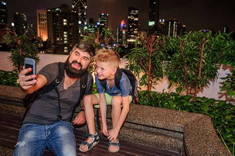 큰 도시에서 백 패 커입니다 아버지와 아들 행복 하 고 흥분 말레이시아 여행에 대 한 함께 밤 시입니다 배경에 대 한 마천루입니다 언덕에서 볼 2명에 대한 스톡 사진 및