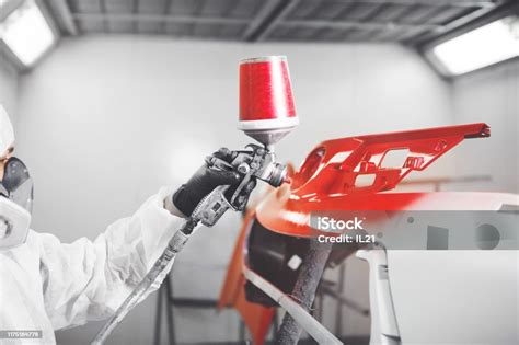 흰색 페인트 챔버에 빨간 자동차 범퍼를 그리는 에어 브러시 분쇄기와 보호 장갑에 화가 노동자를 스프레이 산업에 대한 스톡 사진
