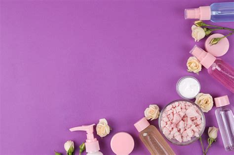 밝은 보라색 배경에 신선한 장미와 분홍색 병에 얼굴과 몸에 대한 화장품 크림과 로션 바다 소금과 비누 스파 위에서 볼 수 있습니다 텍스트 공간 0명에 대한 스톡 사진 및