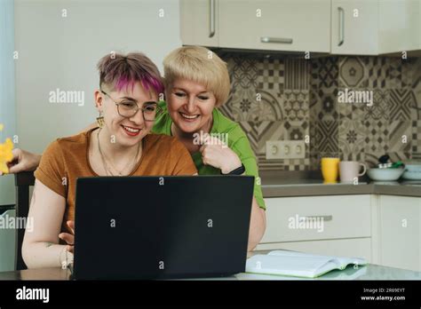 Adult Modern Mother And Non Binary Daughter Using Laptop Together