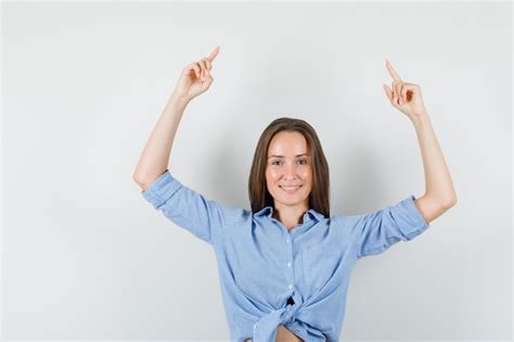 Giovane Signora Che Indica In Su In Camicia Blu E Che Sembra Felice Foto Gratis