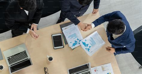 그룹 비즈니스 사람들은 사무실의 회의 테이블에서 악수하고 탑 뷰에서 자신감 있는 샷을 합니다 젊은 사업가와 여성 사업가들은 투자 거래에 대한 동의를 표명합니다 사진