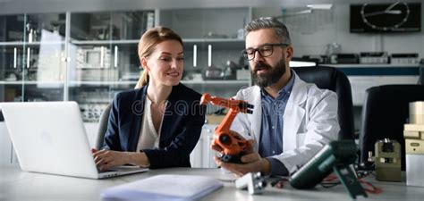 robotics engineers working on laptop and desinging modern robotic arm