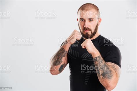 팔에 문신을 새는 진지한 남자의 클로즈업 이미지는 주먹을 꽉 쥐고 흰색 배경 위에 고립 된 펀치에 대한 준비로 카메라에 포즈를 취합니다 강사에 대한 스톡 사진 및 기타