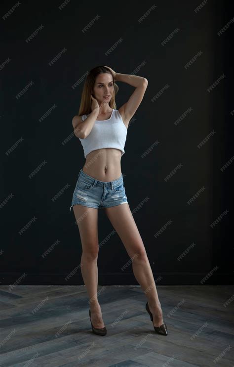 Premium Photo Young Woman In A White Tank Top And Denim Shorts On A