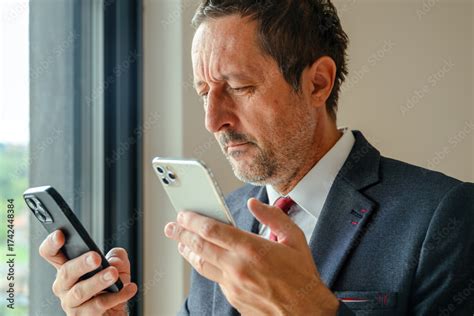 Businessman Using Two Smartphones Simultaneously Trying To Synchronize