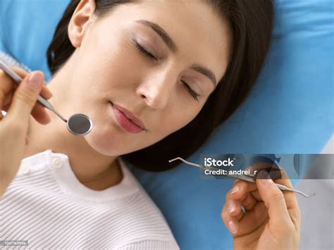 치과 진료소에서 치과 의사에 의해 검사되는 웃는 갈색 머리 여자 환자의 입 근처에 치과 기구를 들고 의사의 손 건강한 치아 및 의학 개념 갈색 머리에 대한 스톡 사진 및