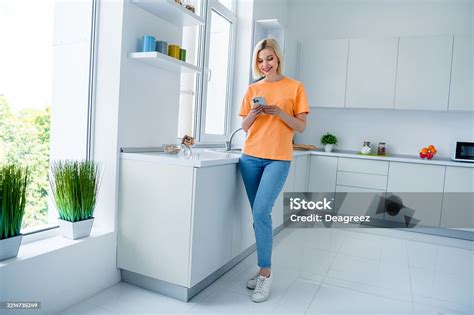 스마트 가제트를 사용하는 레이디 블로거의 사진 소셜 네트워크 페이스 북 인스 타 그램에서 뉴스를 읽고 현대 부엌에서 Brand Name Smart Phone에 대한 스톡