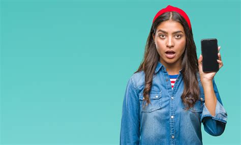 격리 된 배경 위에 깜짝 얼굴 두려워 하 고 공포 식으로 흥분 충격에서 무서 워 스마트폰의 화면을 보여주는 젊은 아름 다운 아랍 여성 보여주기에 대한 스톡 사진 및 기타