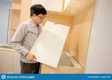Asian Male Furniture Assembler Installing Cabinet Panel Stock Image