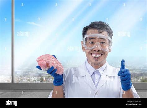 Asian Nerd Scientist Standing And Showing Thumb Up While Holding A Human Brain In The Laboratory