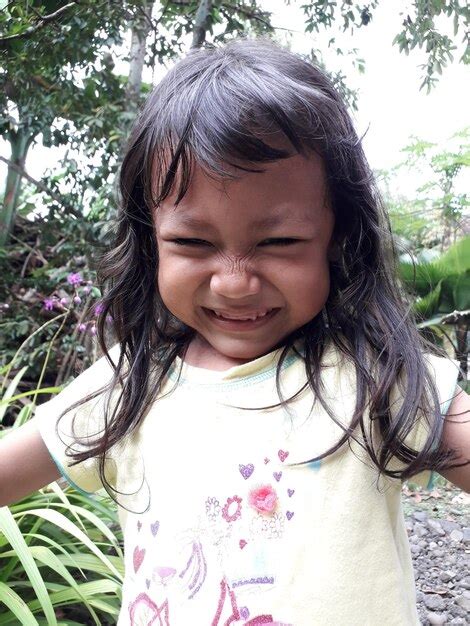 Premium Photo Close Up Of Cute Girl Making A Face Against Trees