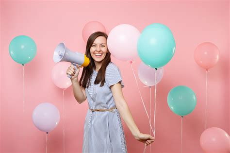 블루 입고 웃는 매력적인 젊은 여자의 초상화 다채로운 공기 Baloons 들고 점멸 복장과 파스텔 핑크 바탕에 확성기 생일 휴가 파티 사람들이 진심으 감정 개념 편지 문서에