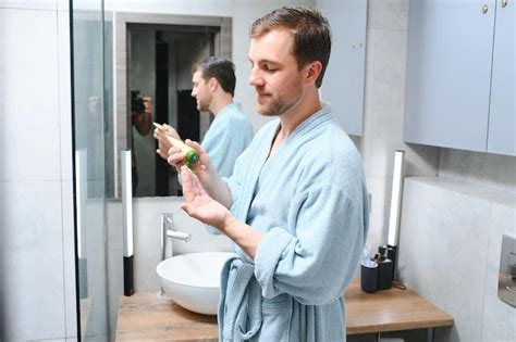 Premium Photo | Handsome young man applying cream on his face in bathroom