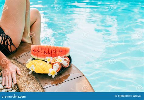 Woman Weared Swimsuit Sitting On Swimming Pool Side With Plate Of Tropical Fruits Stock Photo