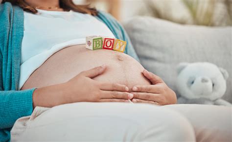 어머니 배 장난감은 소파에서 집에서 휴식을 취하는 어머니를 기대하는 남자 아기와 함께 있습니다 아이 발표 및 아들을 위해 배에 나무 블록이있는 여성과의 임신 알림 30 34