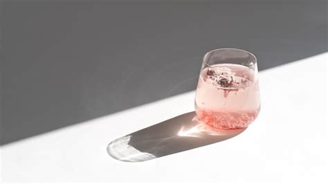 천연 딸기 콜라겐 단백질 파우더 한 잔에 물 한 잔으로 피부 재생을 위한 제품 트렌디 한 음식 첨가제 뷰티 제품 햇빛과 유리의 깊은 그림자와 흰색 배경 하드 햇빛 마시기에